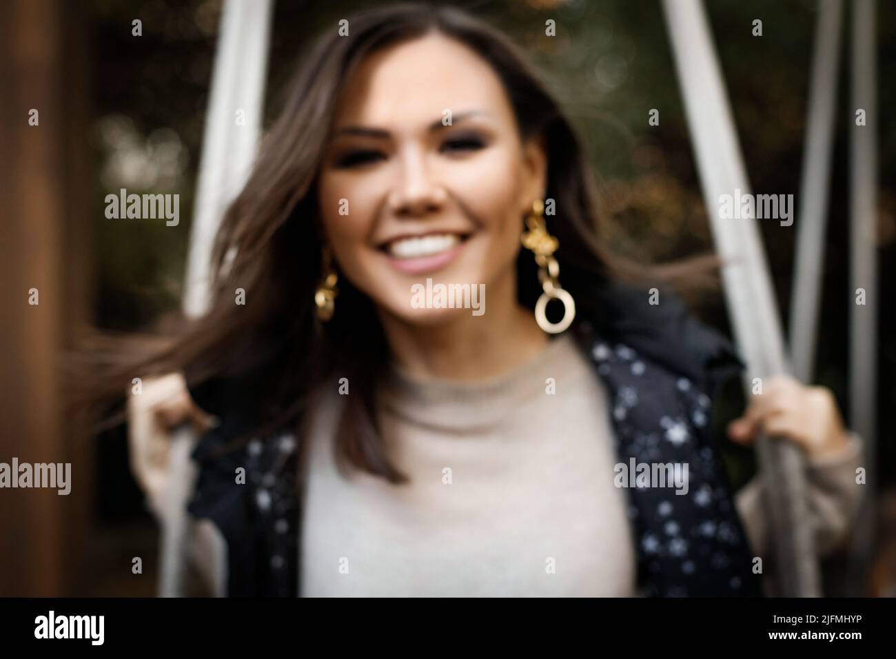 Blurred portrait of a young cheerful central asian woman swinging on a swing outdoor Stock Photo ...