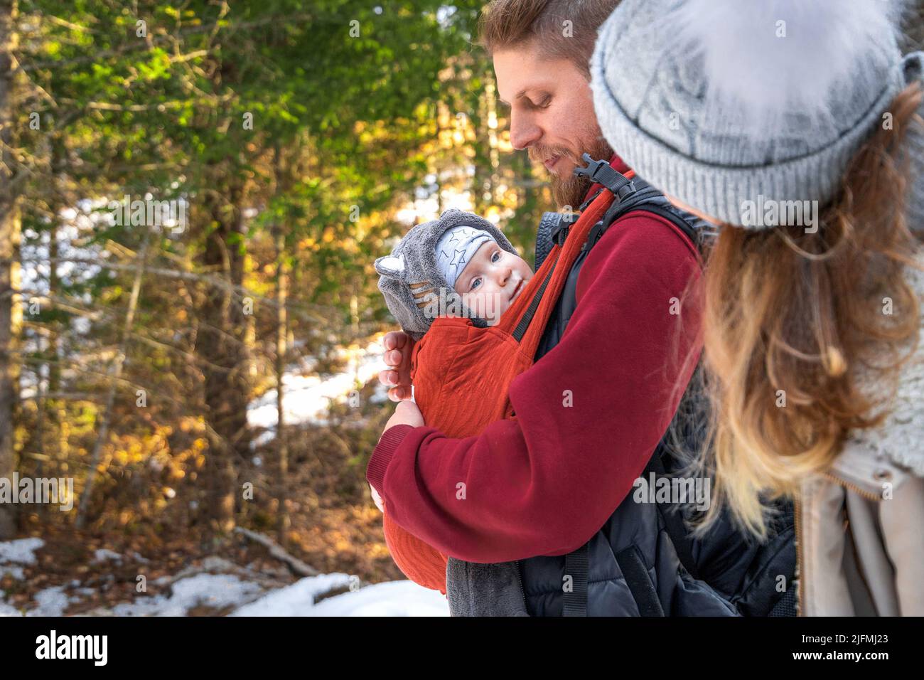 Babywearing winter walk of young parents with their children outdoor ...