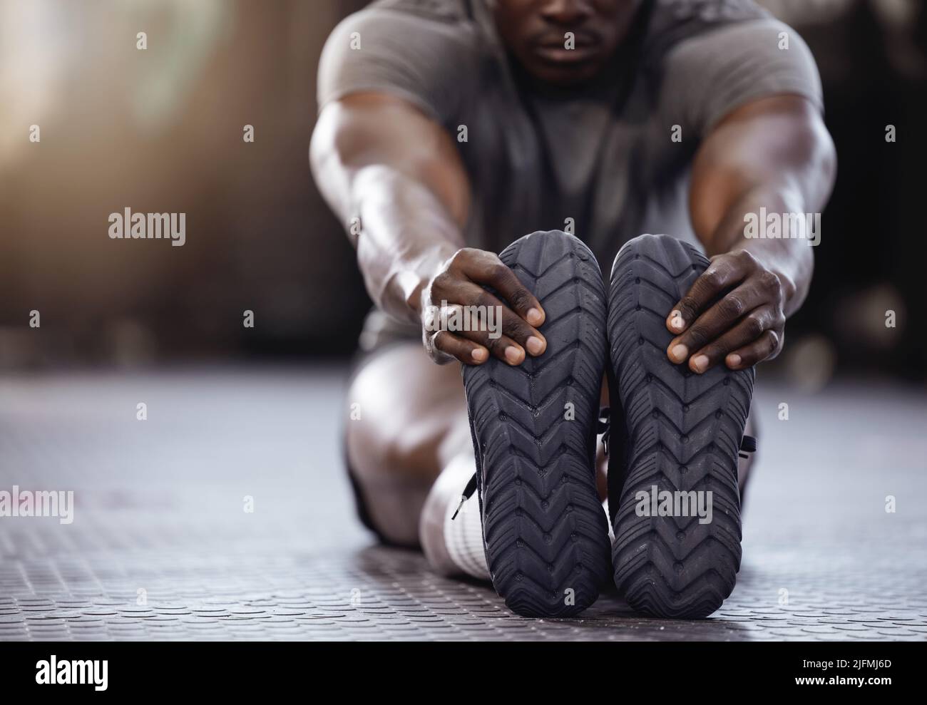 Unknown african american athlete stretching legs while sitting alone in ...