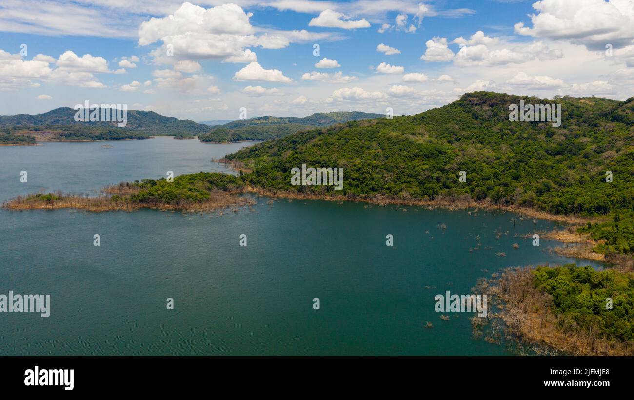 Aerial view of lake among mountains covered rainforest and blue sky ...