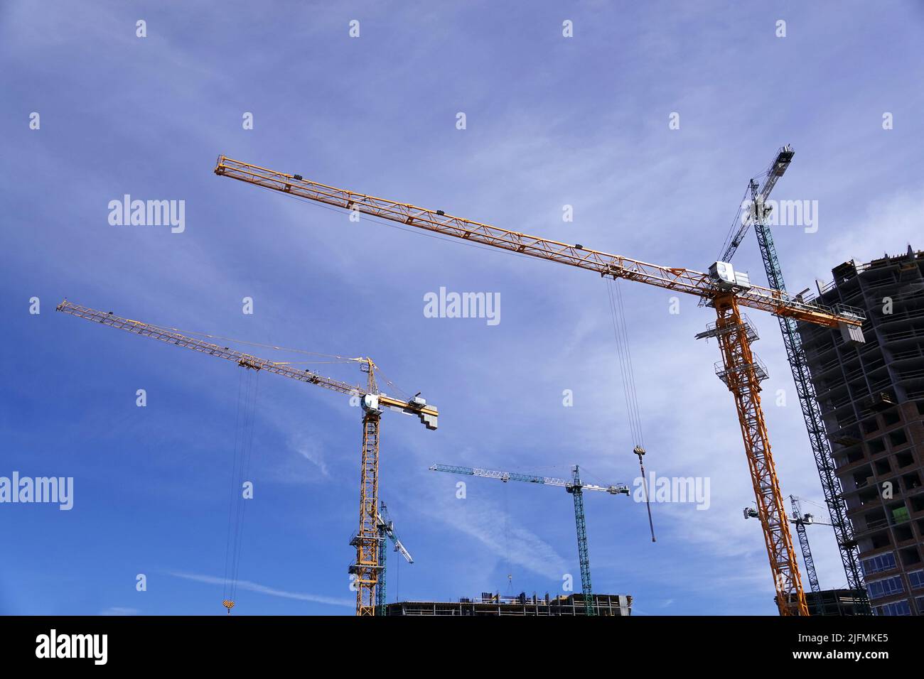 High-rise construction cranes on a background of blue sky Stock Photo ...