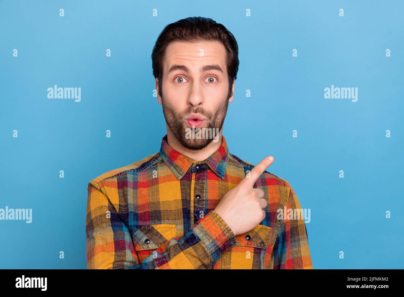 Photo of handsome impressed young guy dressed checkered shirt pointing ...