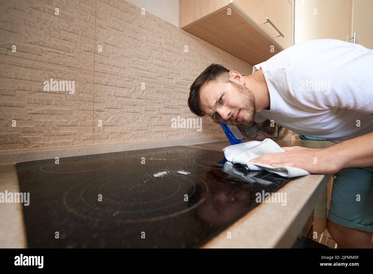Man taking closer look at surface of cooker under cleaning Stock Photo ...