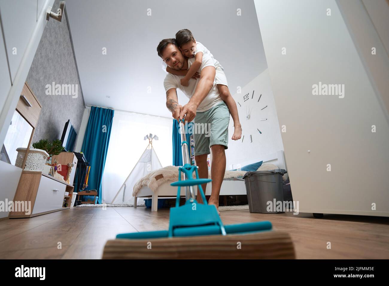 Father with son on back using mop for cleaning floor Stock Photo - Alamy
