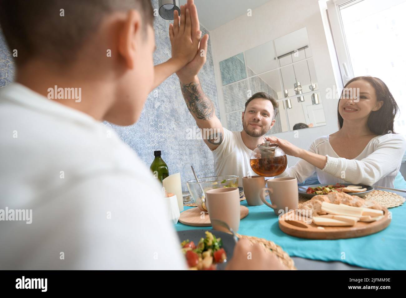 Pleased father and son high fiving during tea party Stock Photo - Alamy
