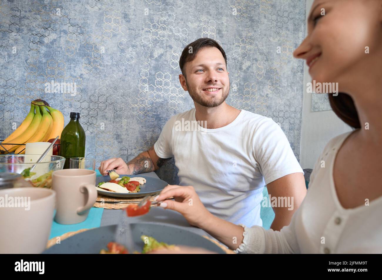 Married couple eating meal together while exchanging pleasant looks ...