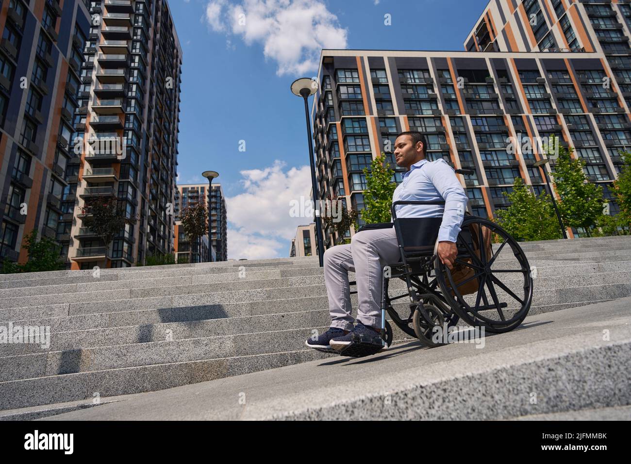 Disabled male person descending concrete staircase in business district ...