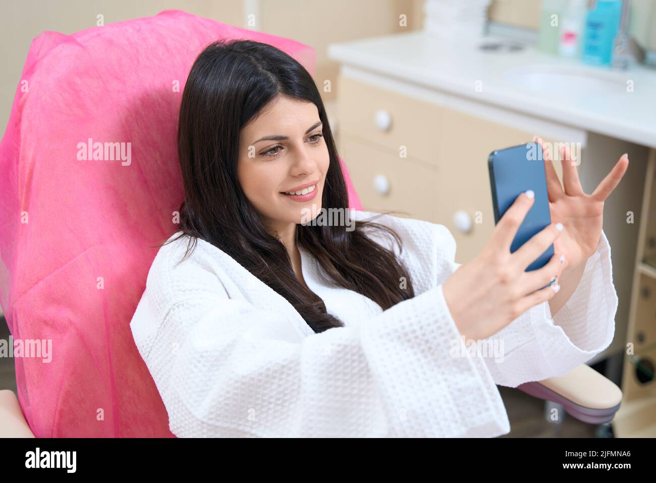 Patient takes selfie after rejuvenation procedures in aesthetic ...