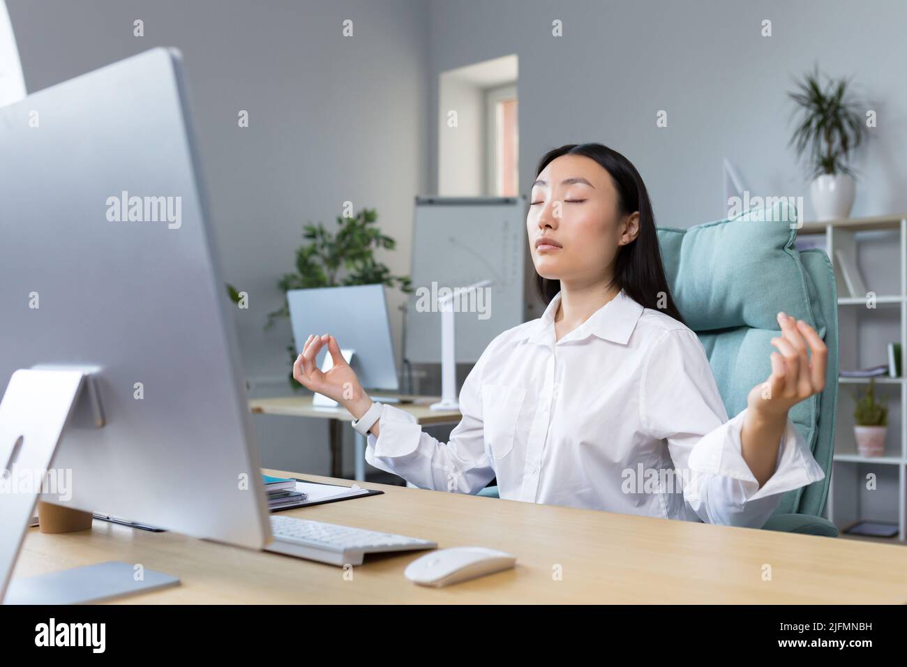 Asian business woman working in the office, resting and meditating ...
