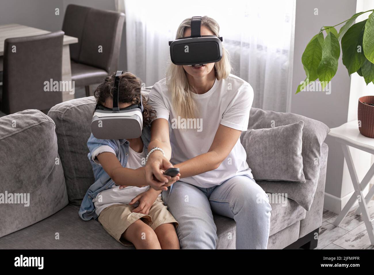 Mother and child wearing virtual reality headset vr glasses in living ...