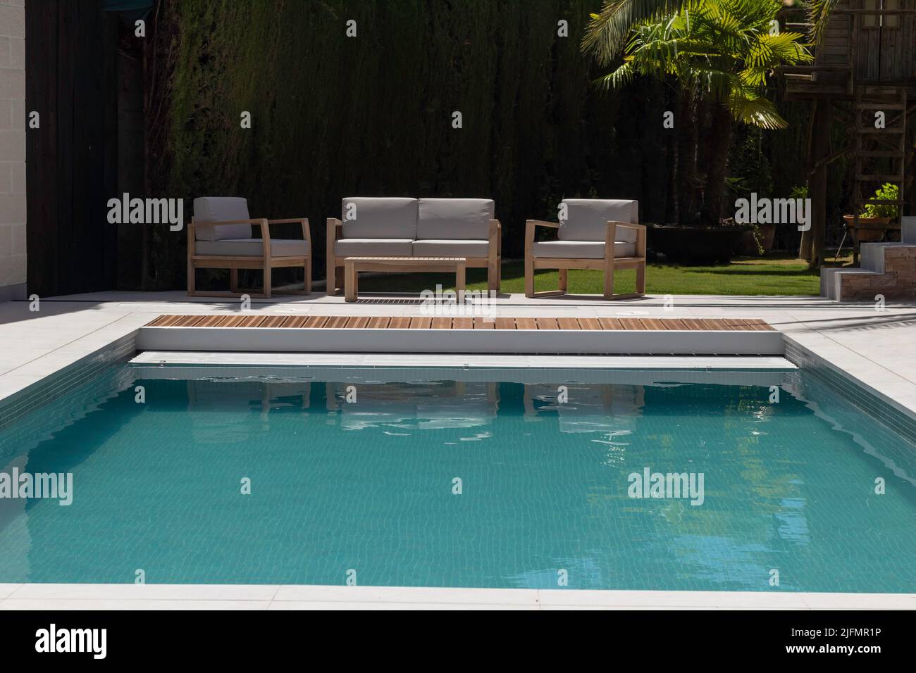 Front view of swimming pool with chill out sitting area and vegetation ...