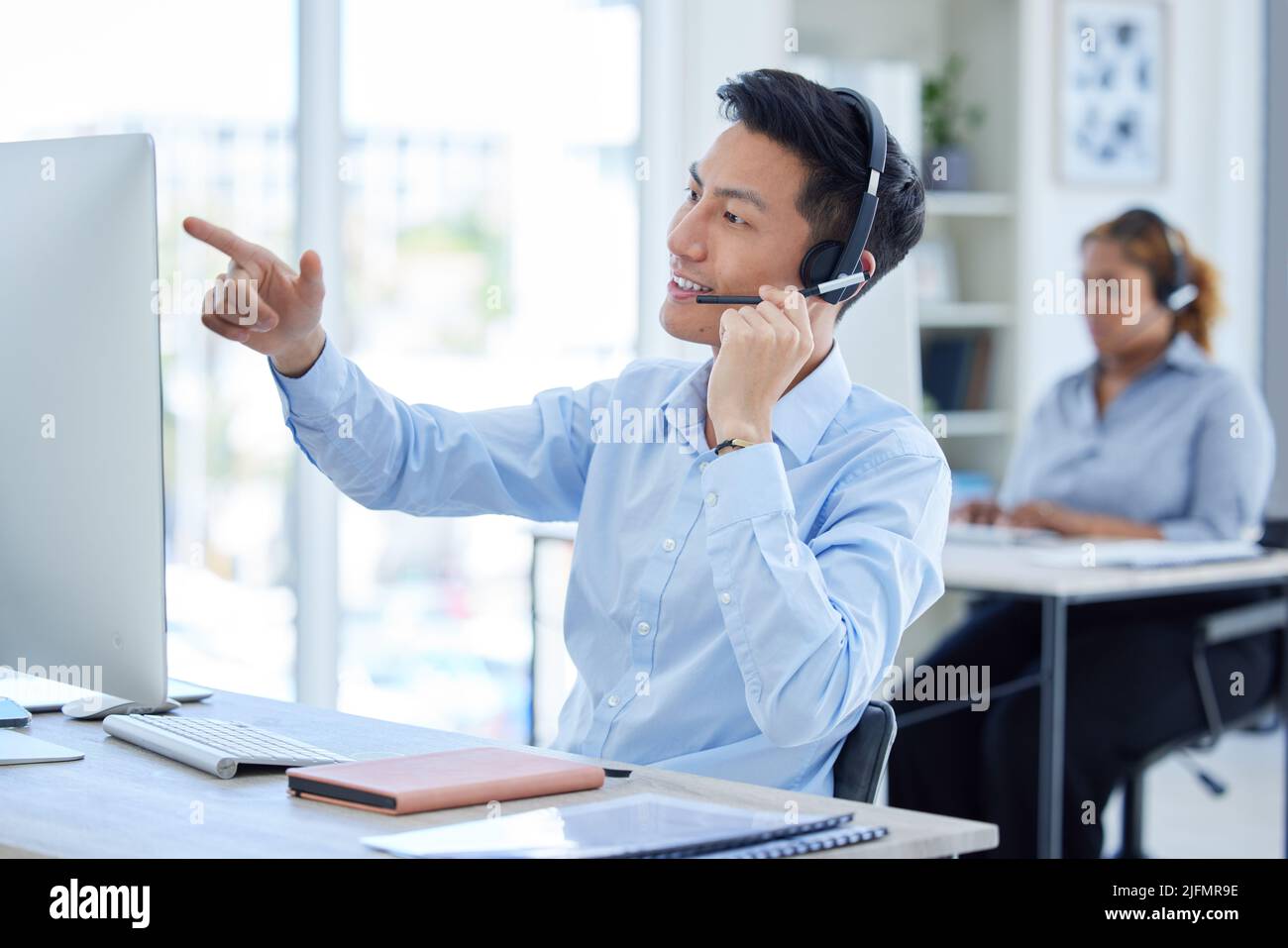 One young asian male call centre telemarketing agent talking on a ...