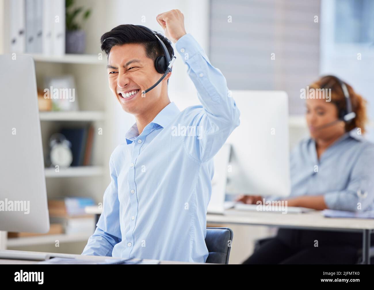 One happy young asian male call centre telemarketing agent cheering ...