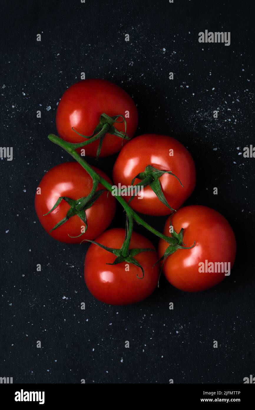 Fresh tomato bunch on black background Stock Photo - Alamy