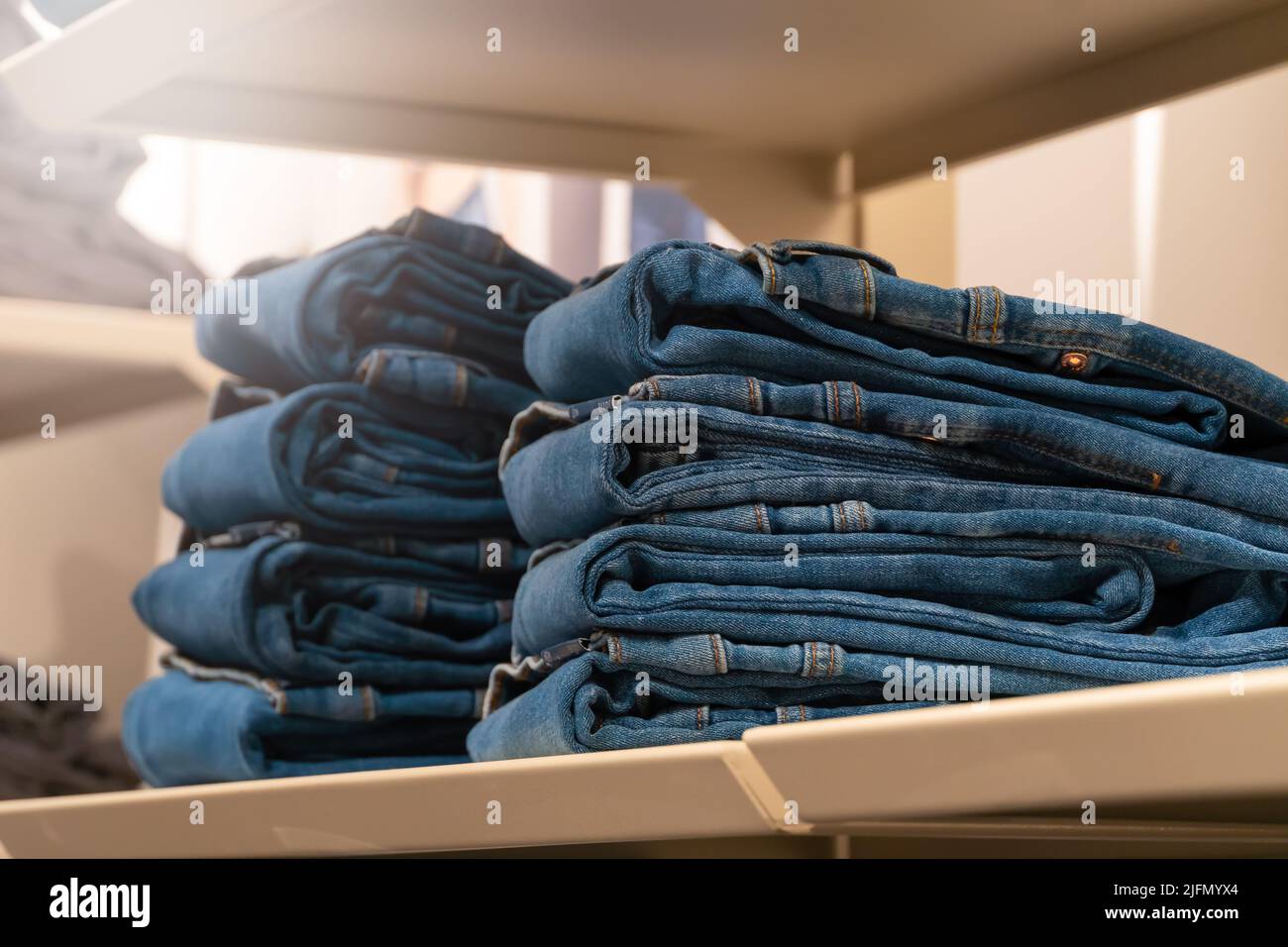 Stacks of jeans on a shelf in a mall store. Concept of buying, selling ...
