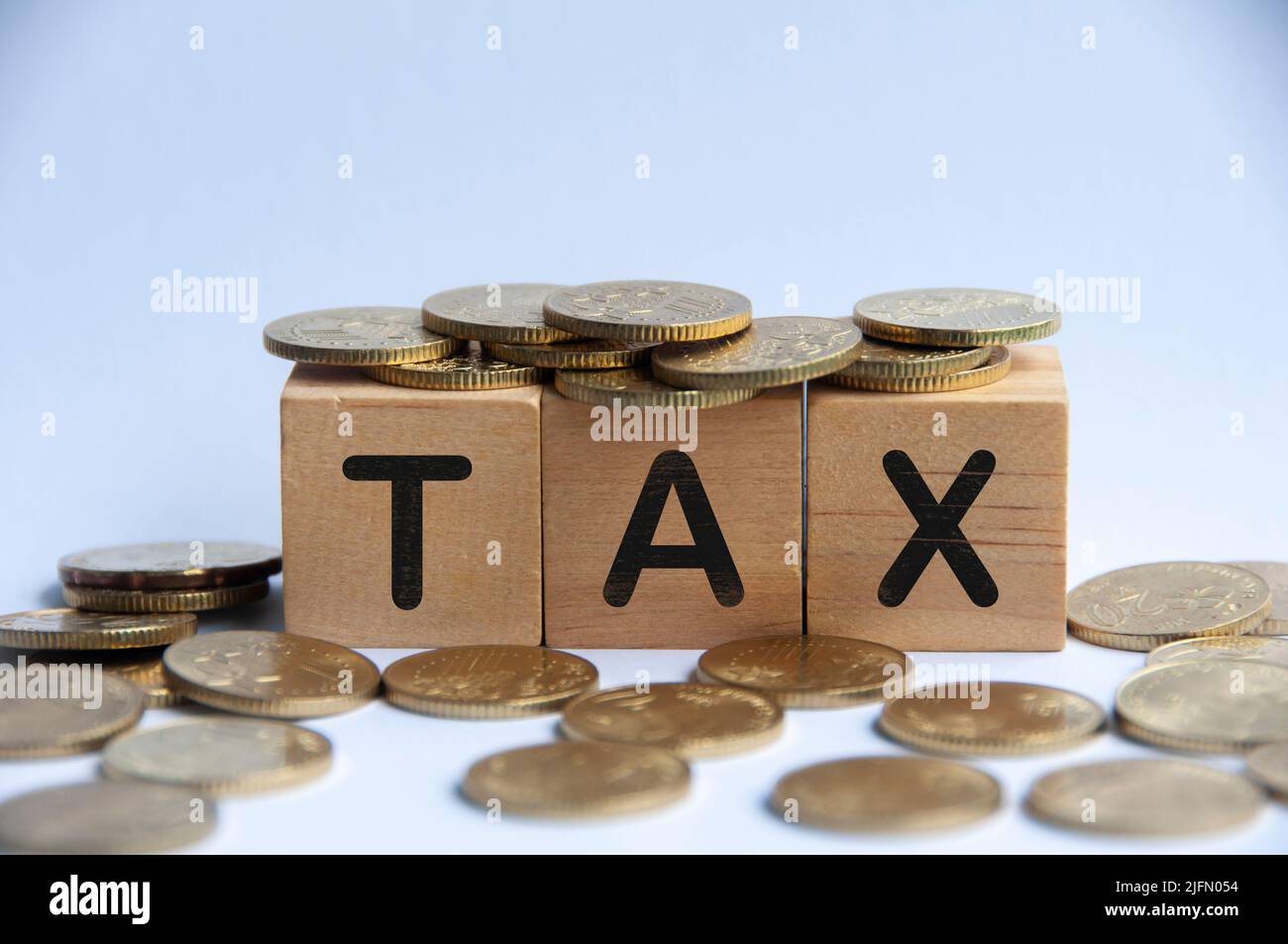 Tax word on wooden block surrounded with gold coins. Taxation concept ...