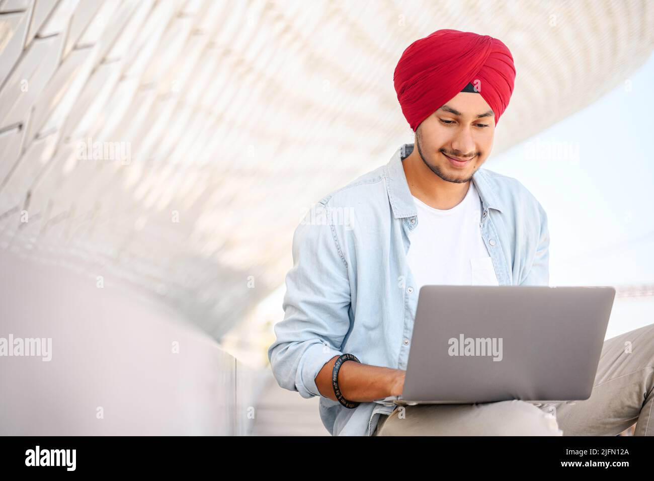 Indian freelancer man in traditional turban pagg sitting outdoors with ...