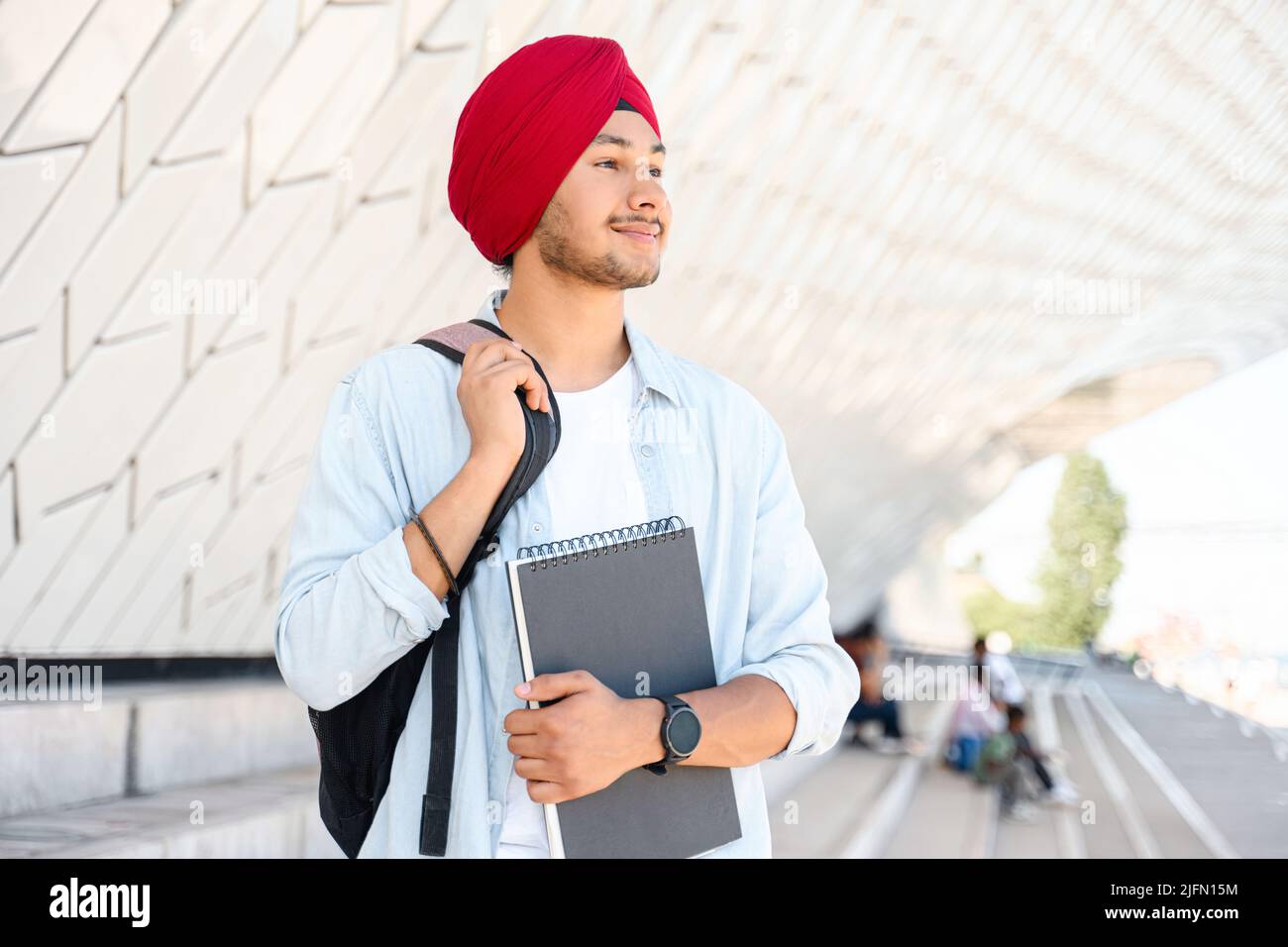 Inspired Indian male student with backpack holding laptop outdoors ...