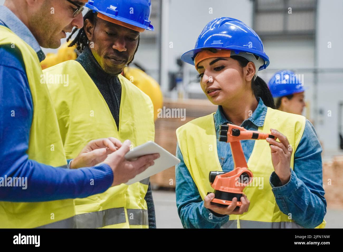 Multiracial engineers working inside automation and robotics facility ...