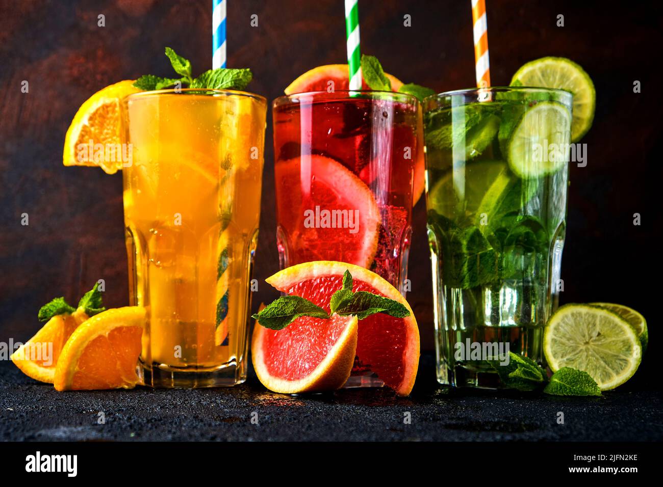 Three classic cocktail glasses on stone black table on dark background ...