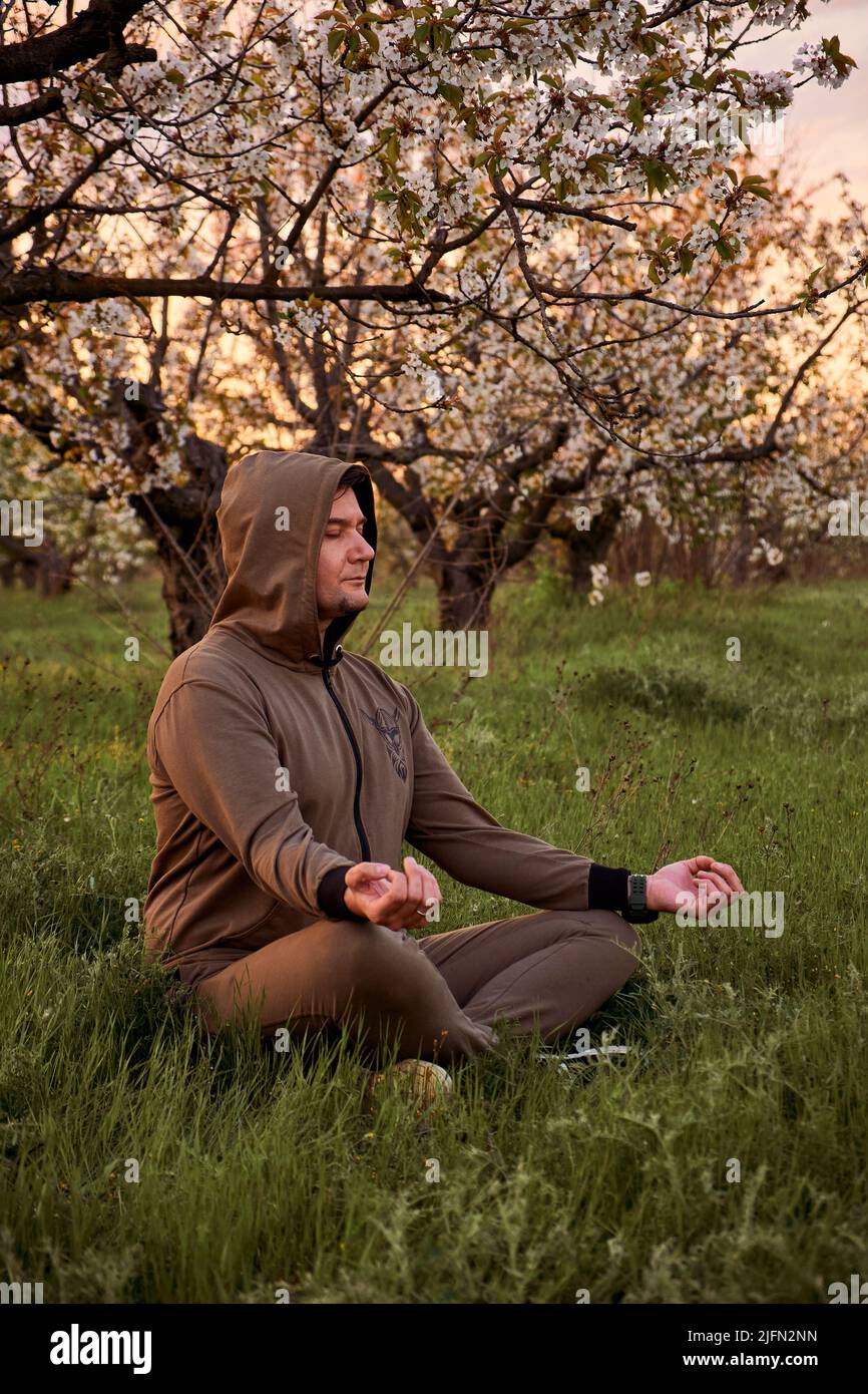 Man meditating in a park at sunset. Healthy lifestyle Stock Photo - Alamy
