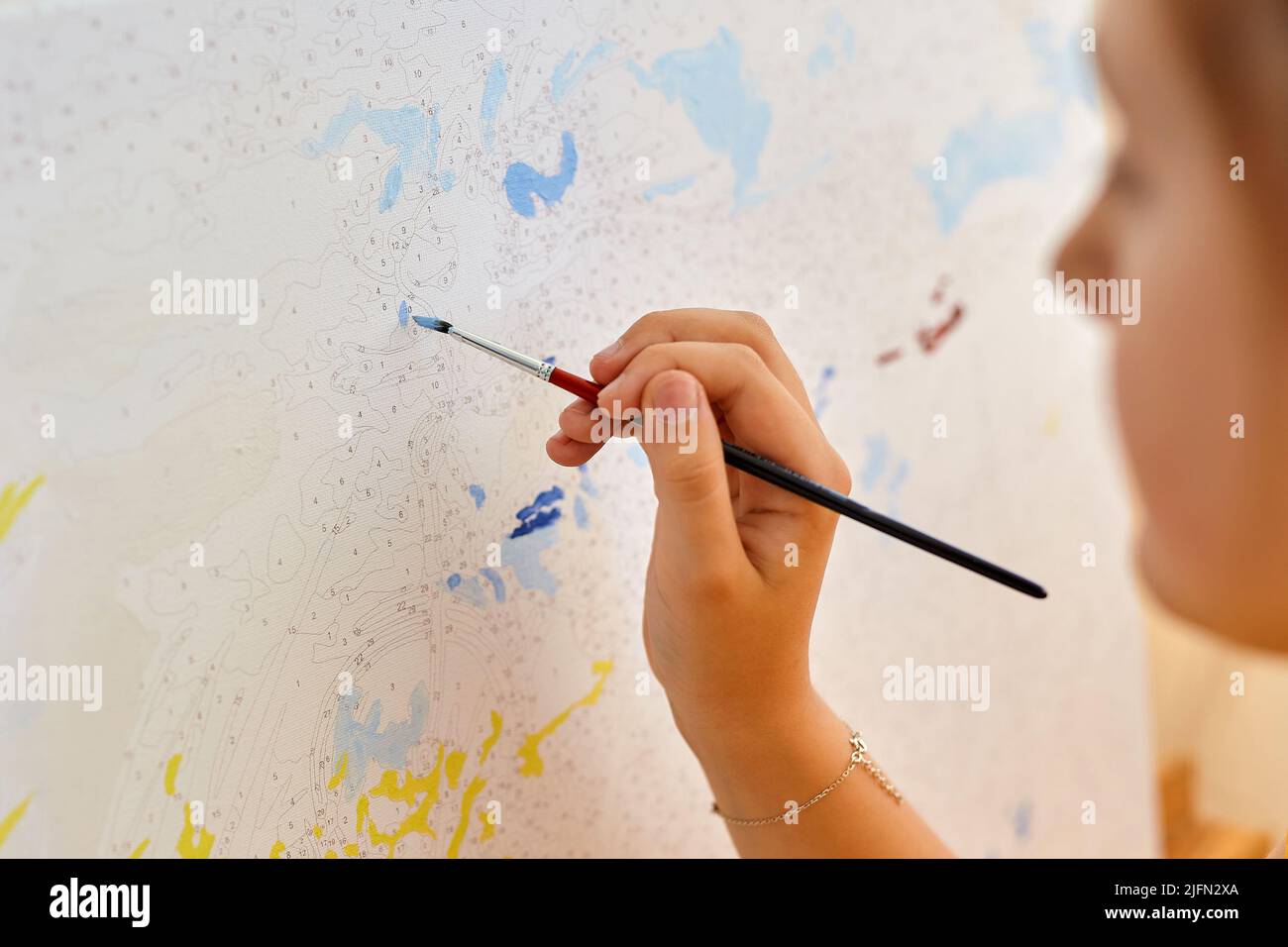 Kid's hand drawing with paintbrush on numbered canvas Stock Photo - Alamy