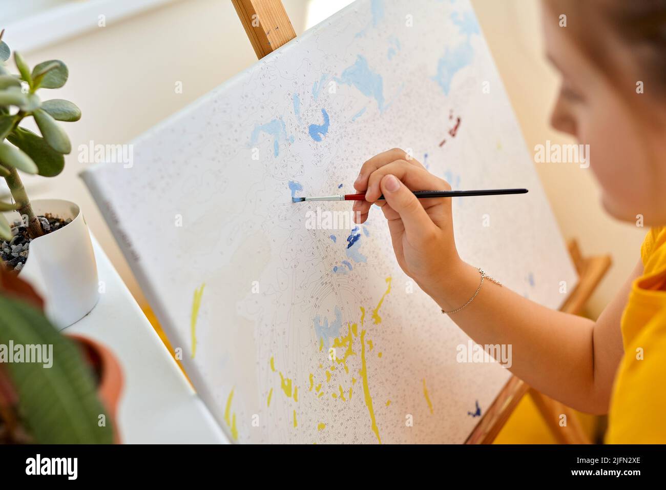 Kid's hand drawing with paintbrush on numbered canvas Stock Photo - Alamy