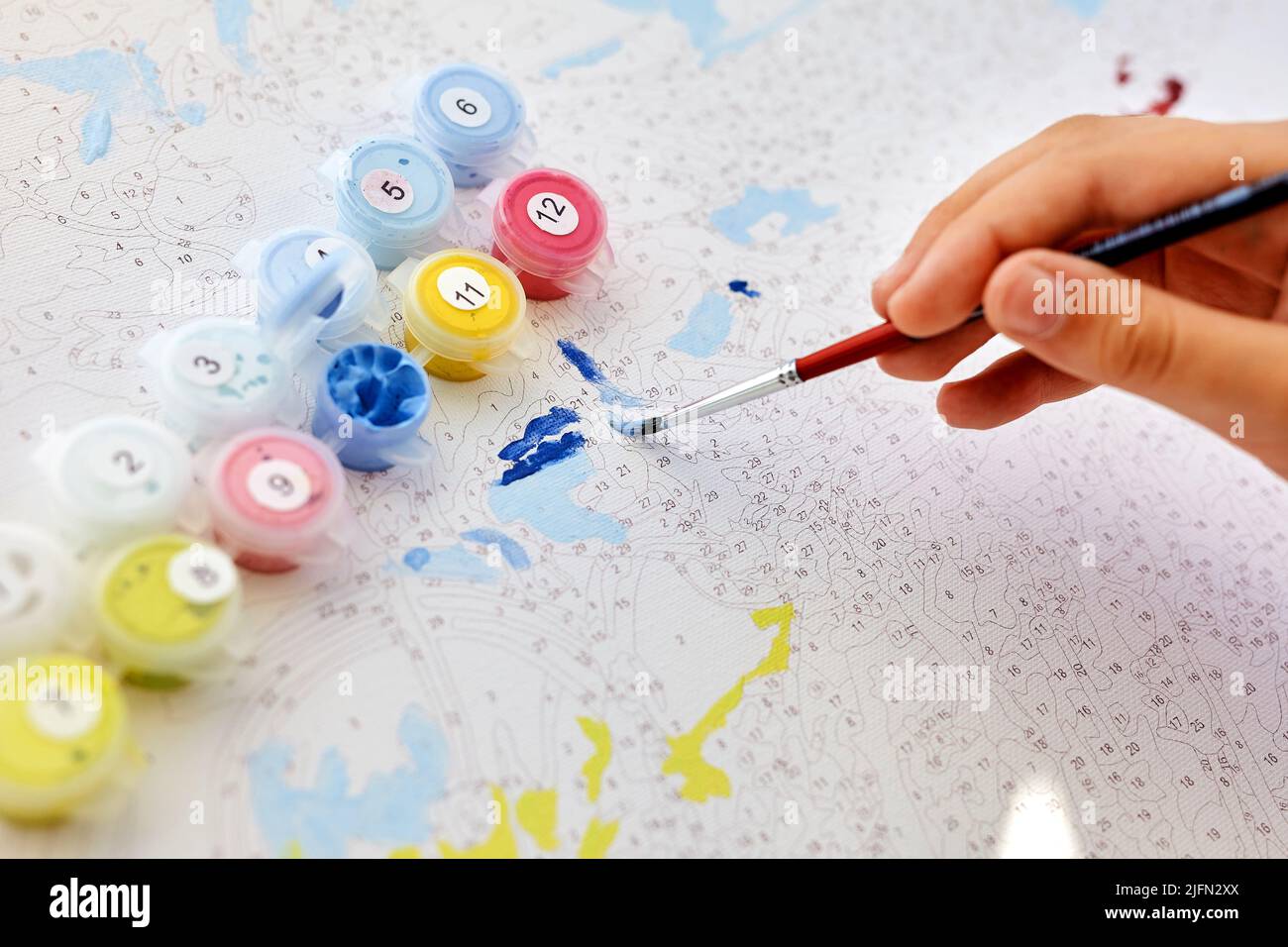 Kid's hand drawing with paintbrush on numbered canvas Stock Photo - Alamy
