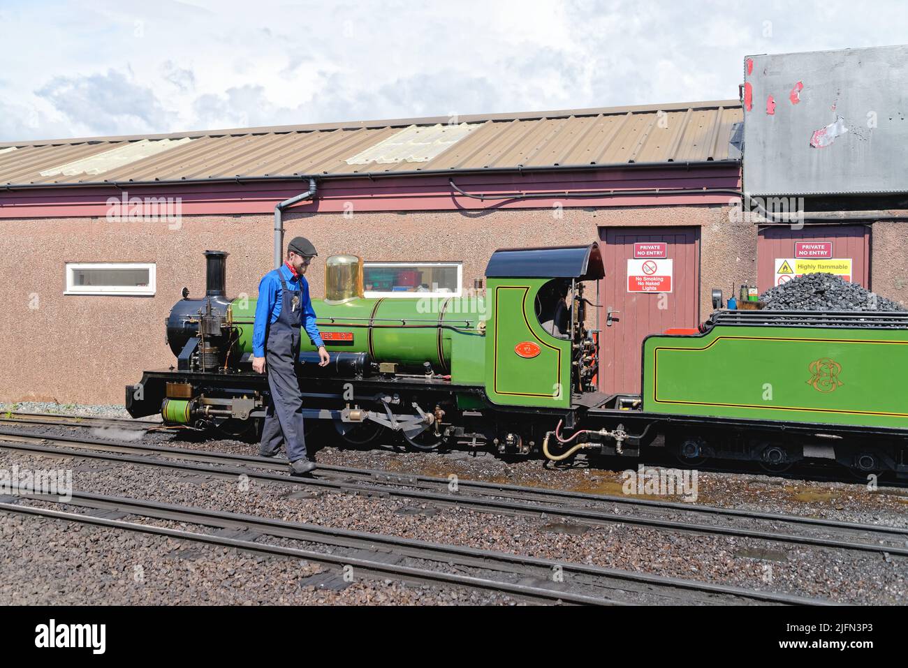 An engine driver by the River Irt steam locomotive at Ravenglass ...