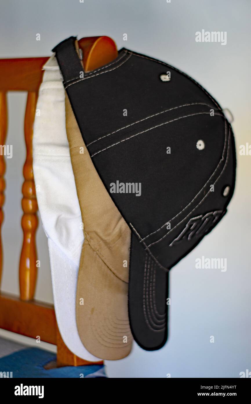 Three baseball caps hang on the back of a kitchen chair Stock Photo - Alamy