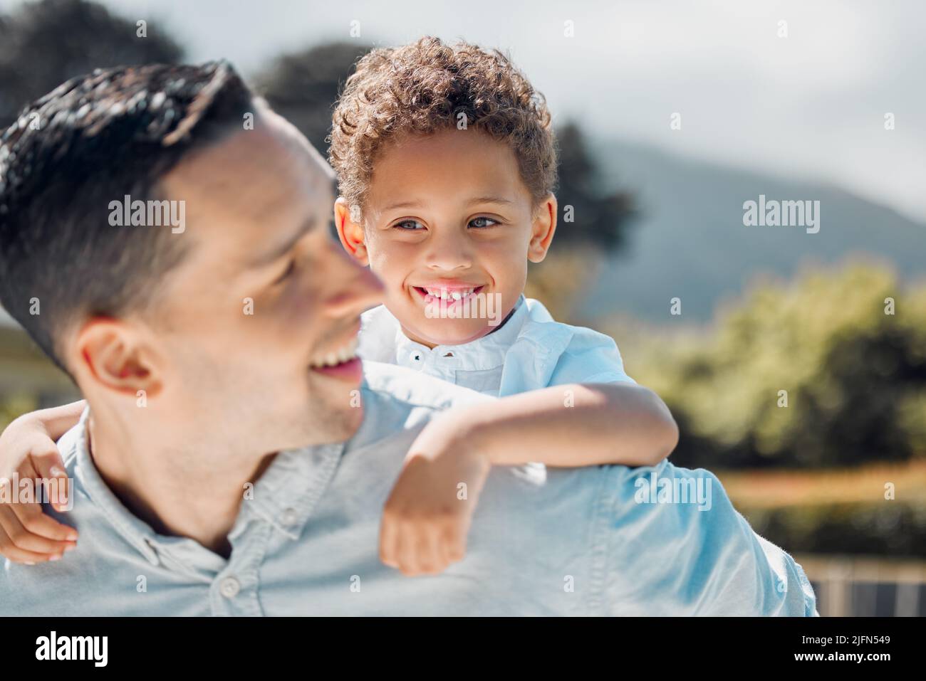 Father carrying boy on back while spending time together outdoors on a ...