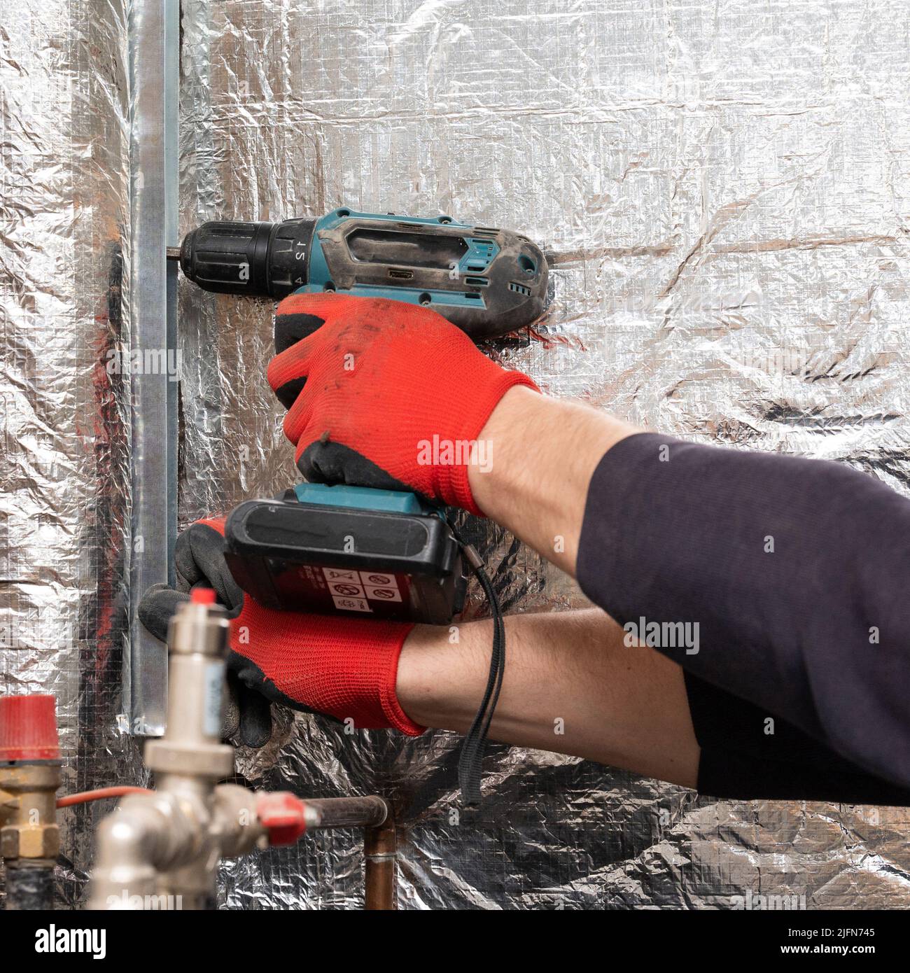 The master screws a metal profile to the wall with a screwdriver ...