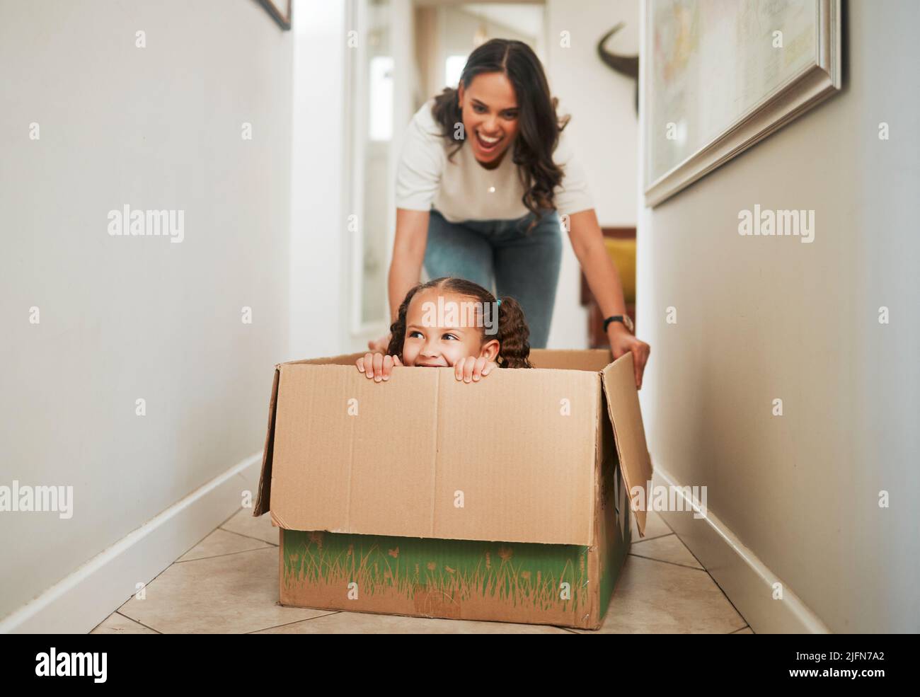 Mother and daughter playing with a cardboard box. Excited little girl ...