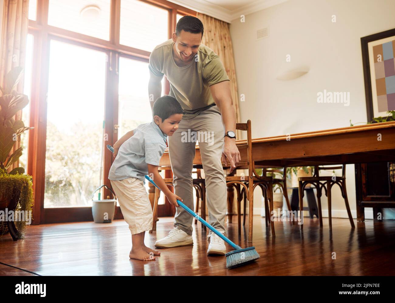 Father pointing to show dust and dirt on wooden floor for son to sweep ...