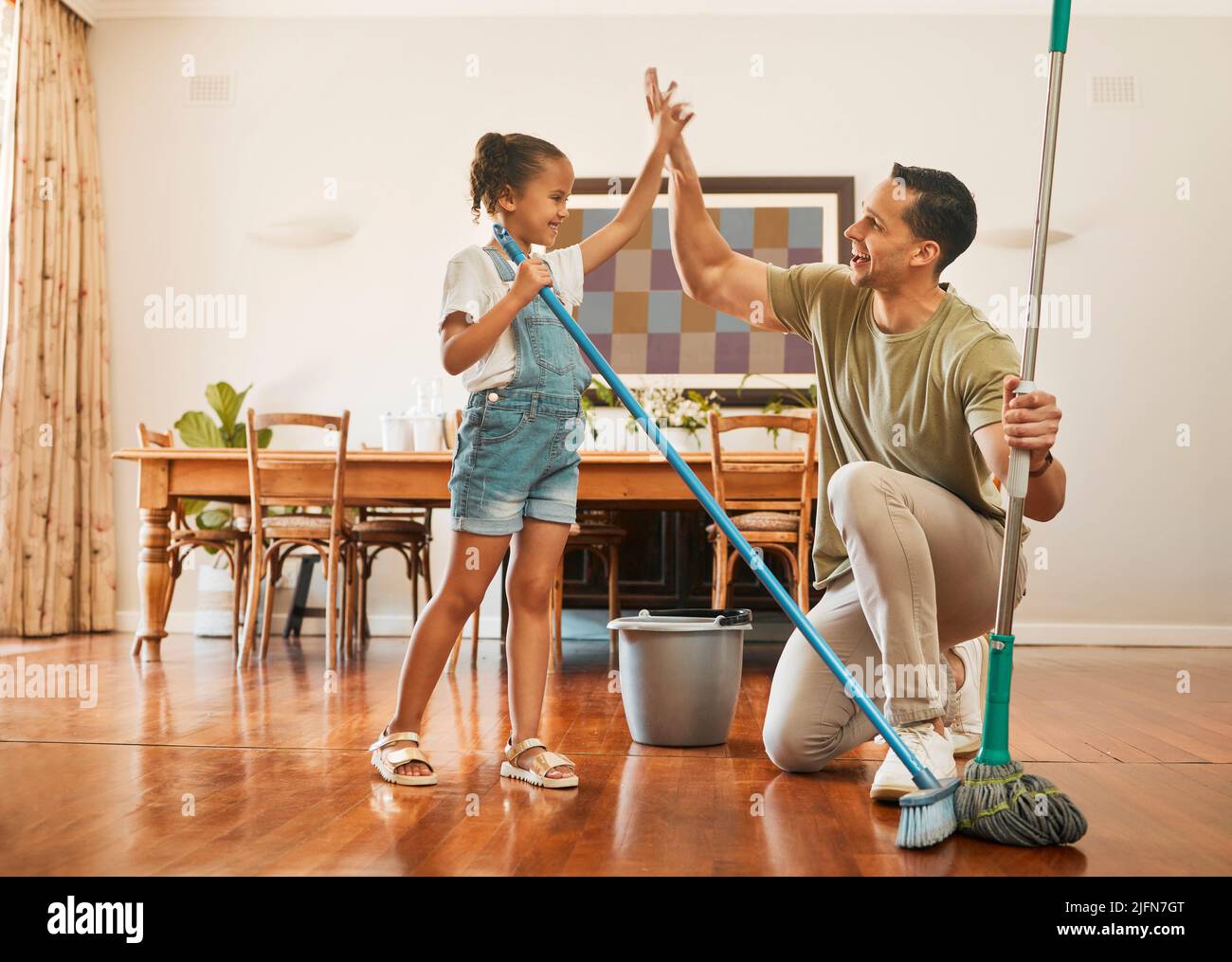 Adorable little girl helping her father sweep and mop wooden floors for ...