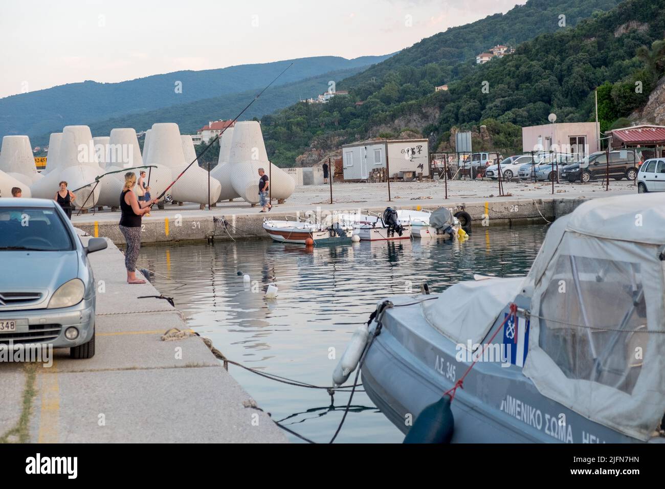 People fishing with fishing rods in the harbor Stock Photo - Alamy