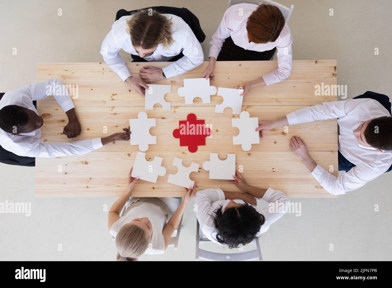 Diverse business people helping in assembling puzzle, cooperation in ...