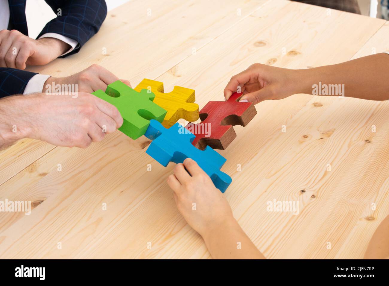 Business people helping in assembling puzzle, cooperation in decision ...