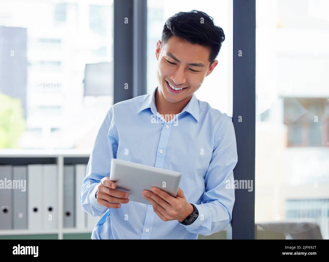 One happy asian business man browsing online on a digital tablet in an ...