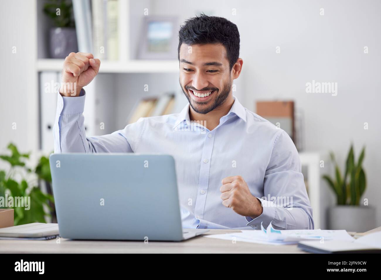 Young happy and excited mixed race businessman cheering with his fist ...