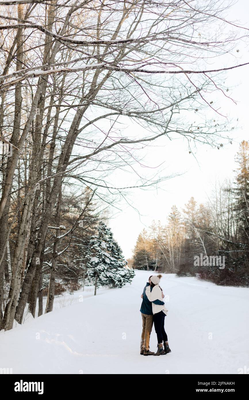 A couple in a distance hugging eachother on the winter ice floor park ...