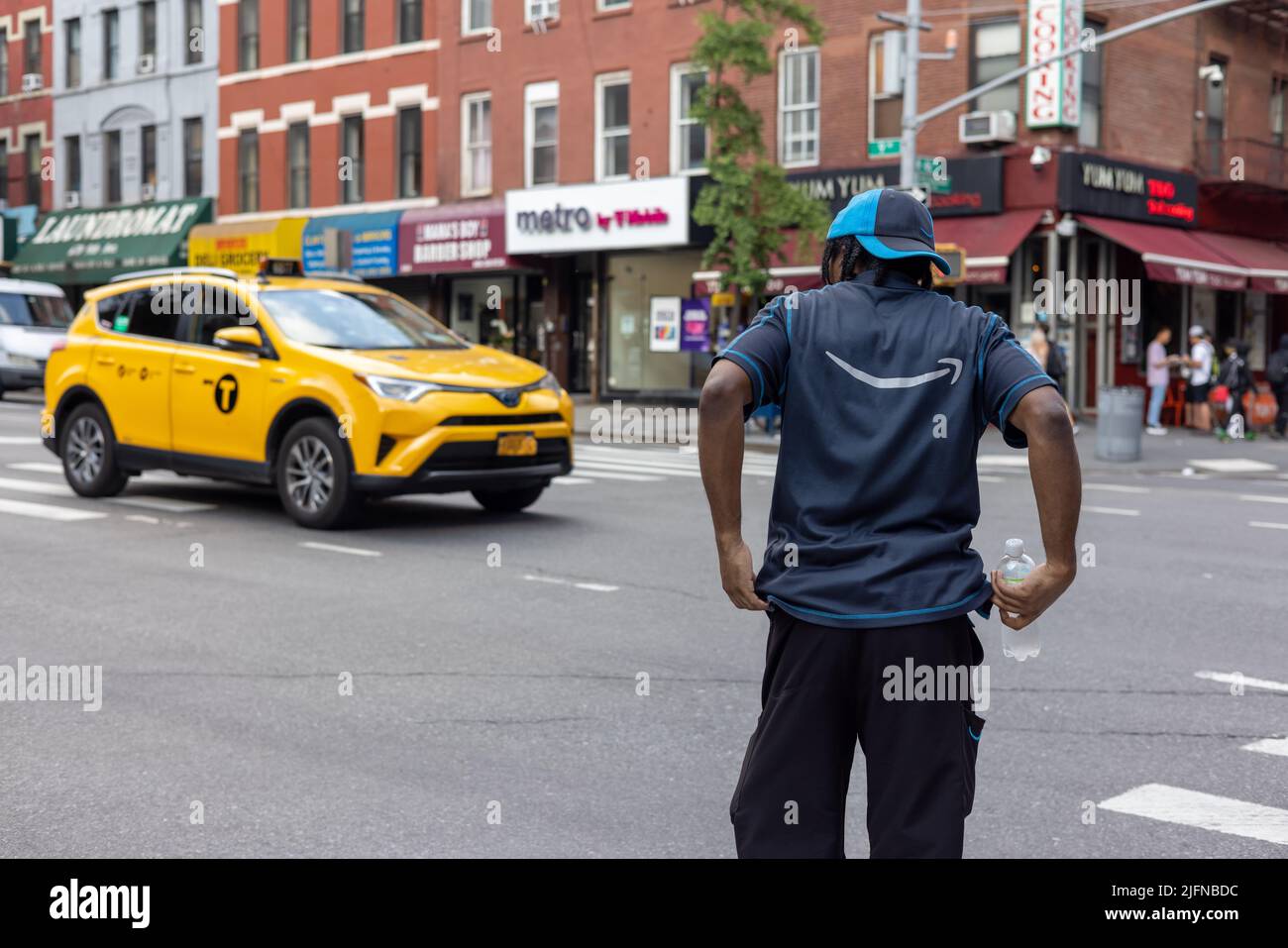 An Amazon delivery worker attempts to cross the street as NYC Taxi ...