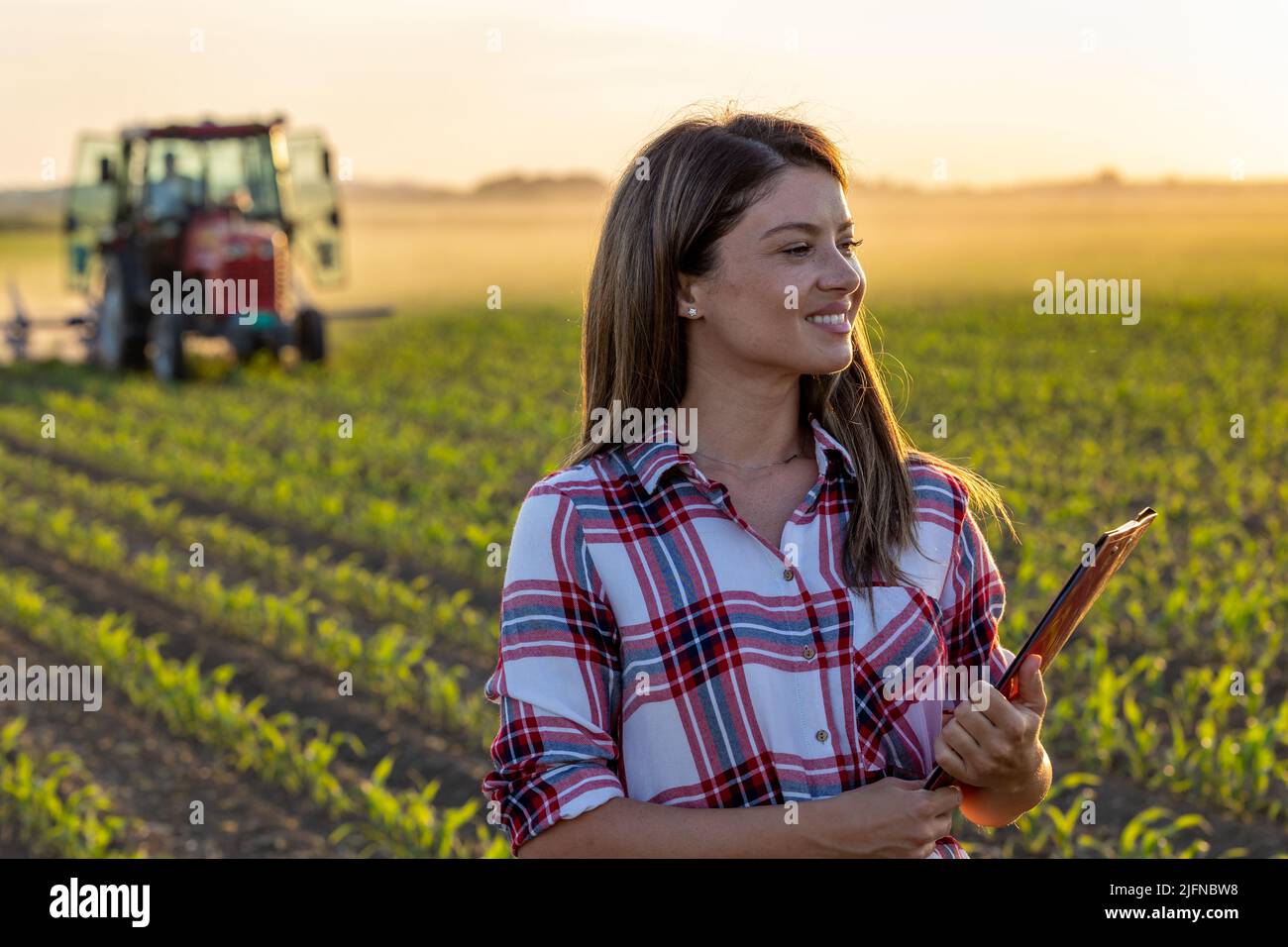 Portrait of pretty young farmer woman holding notepad in front of ...