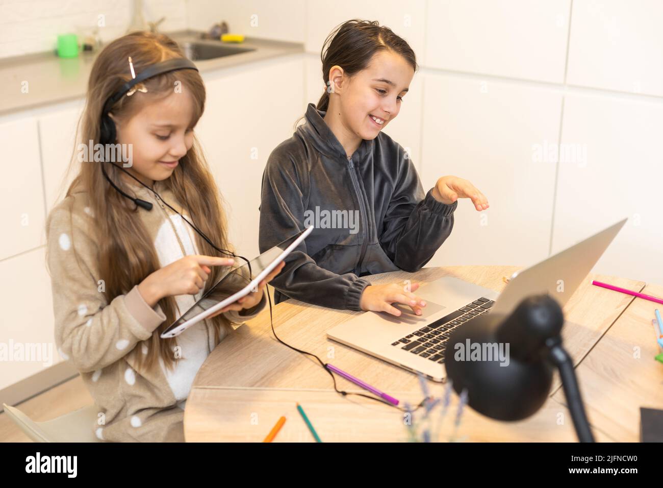 Two child girl students study online with teacher by video call ...
