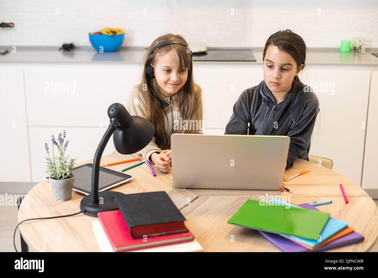 Two child girl students study online with teacher by video call ...