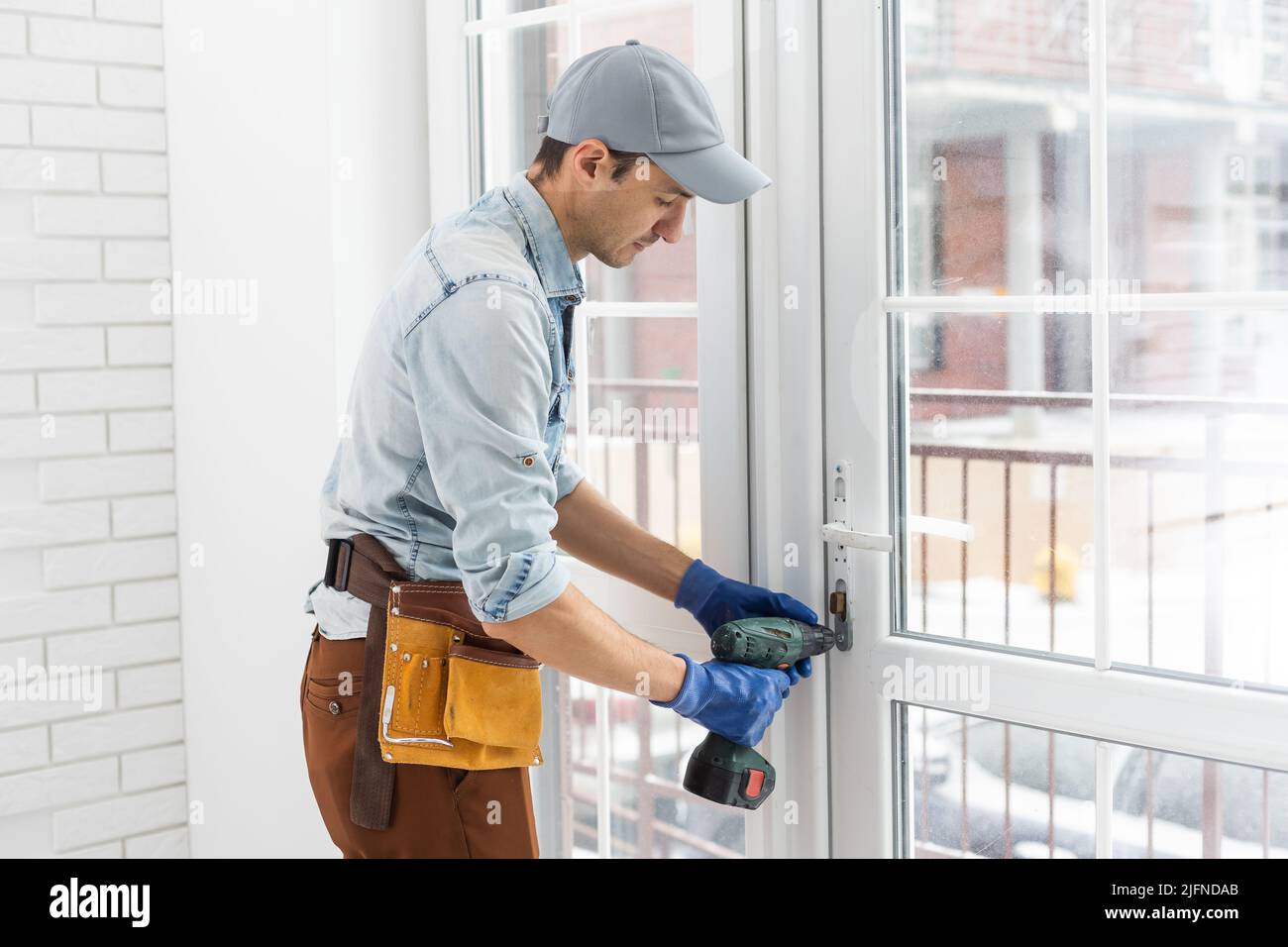 handsome young man installing bay window in a new house construction ...