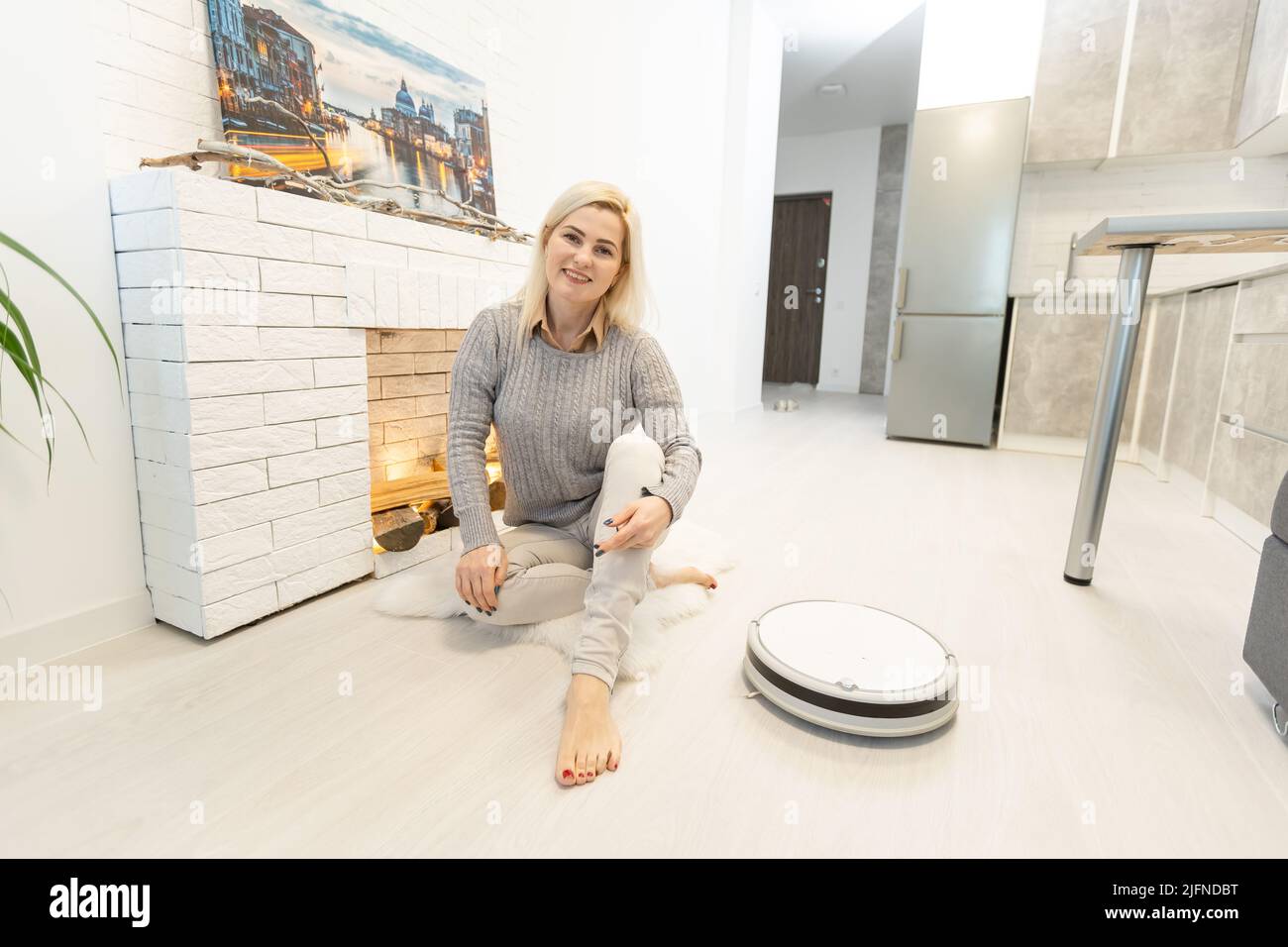 young woman using automatic vacuum cleaner to clean the floor ...
