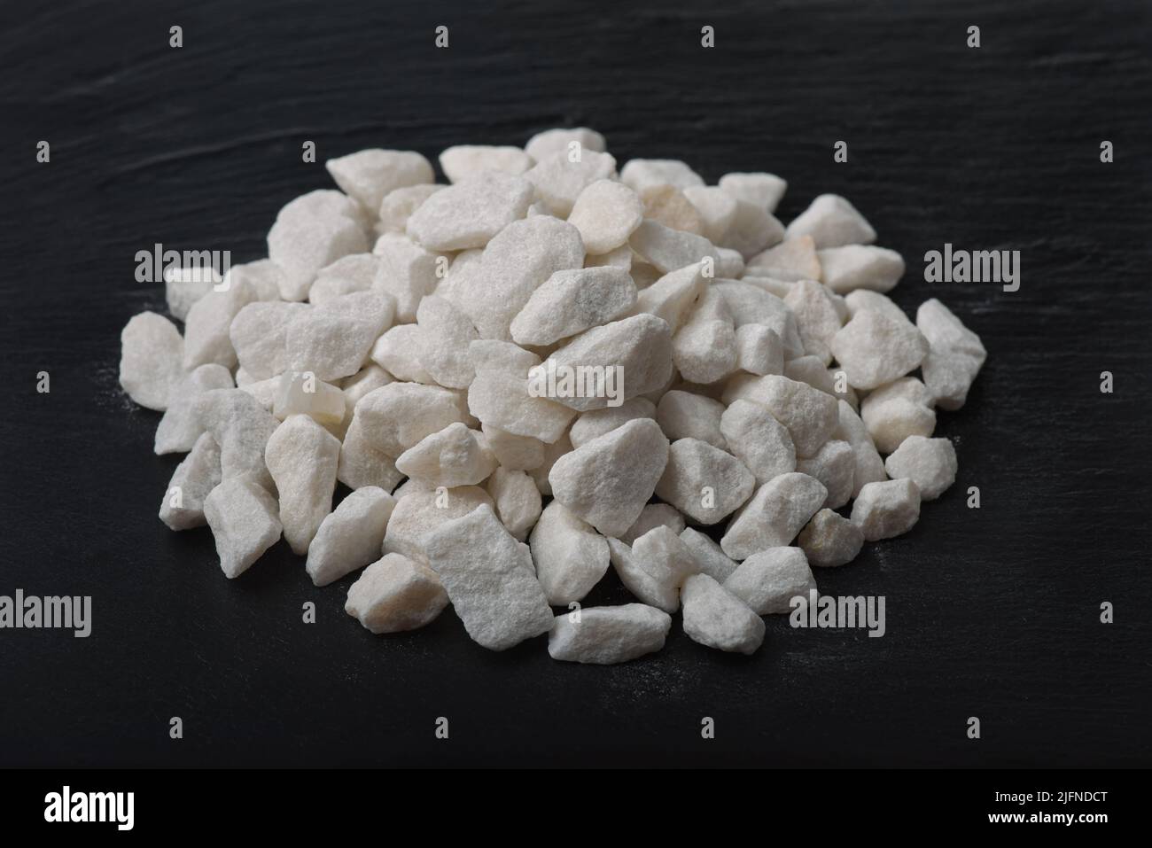 Pile of natural crushed marble chips on black stone surface Stock Photo ...