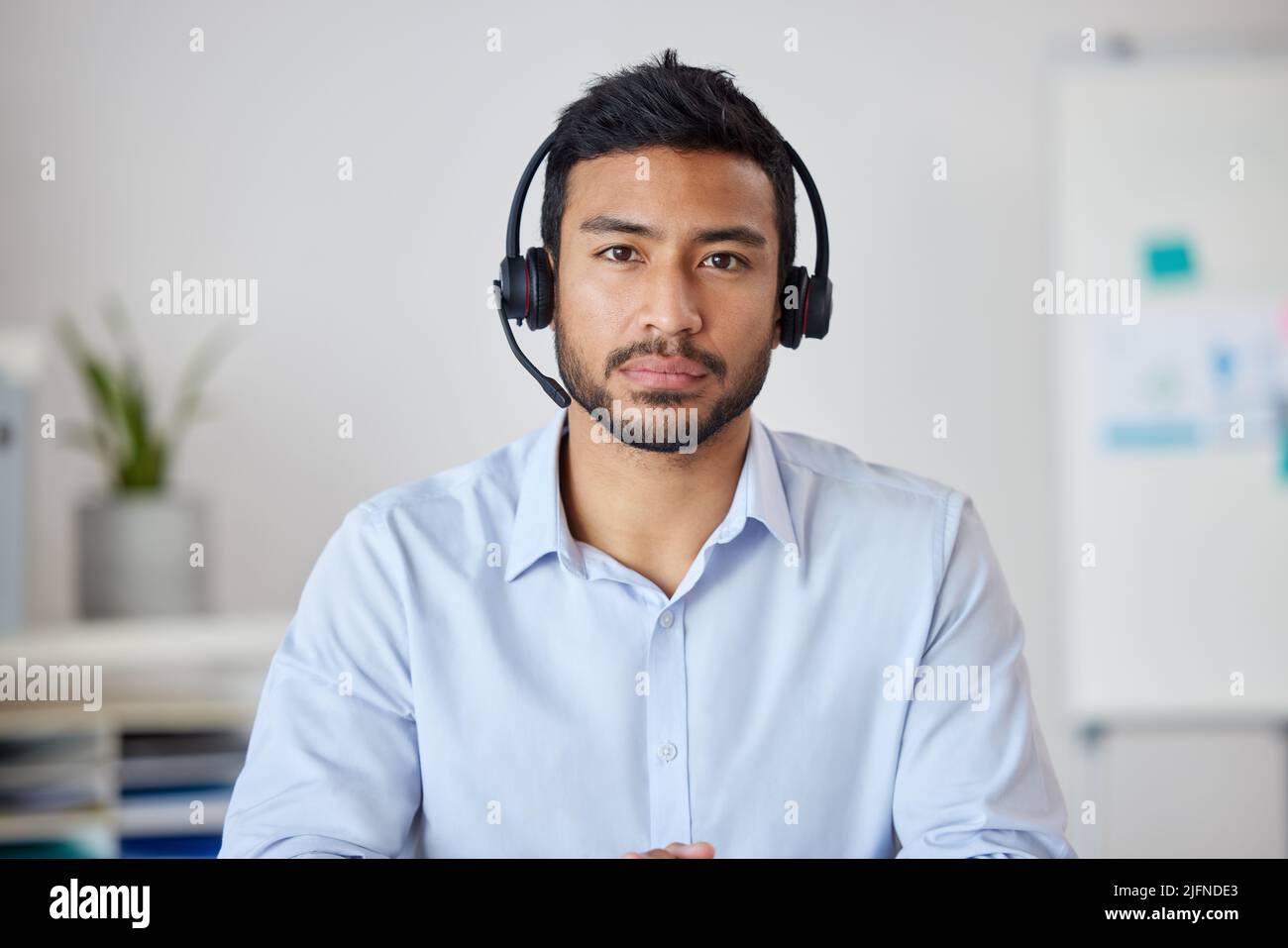 Portrait of a young mixed race businessman working in a call center ...