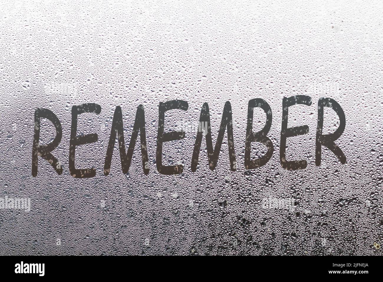 Foggy glass on window with written finger word remember overcast wet ...